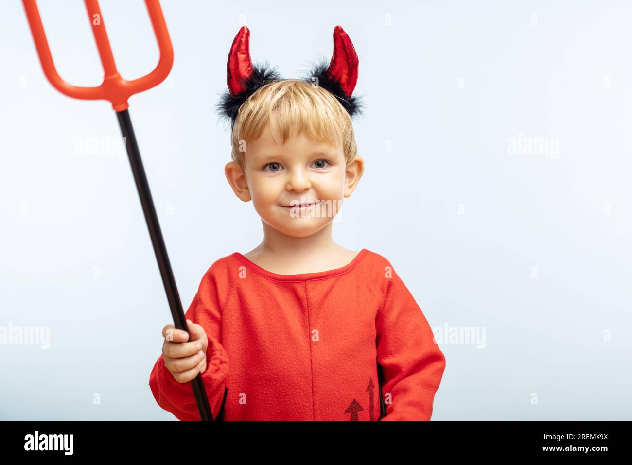 Happy cheerful boy in devil costume with trident on blue background ...