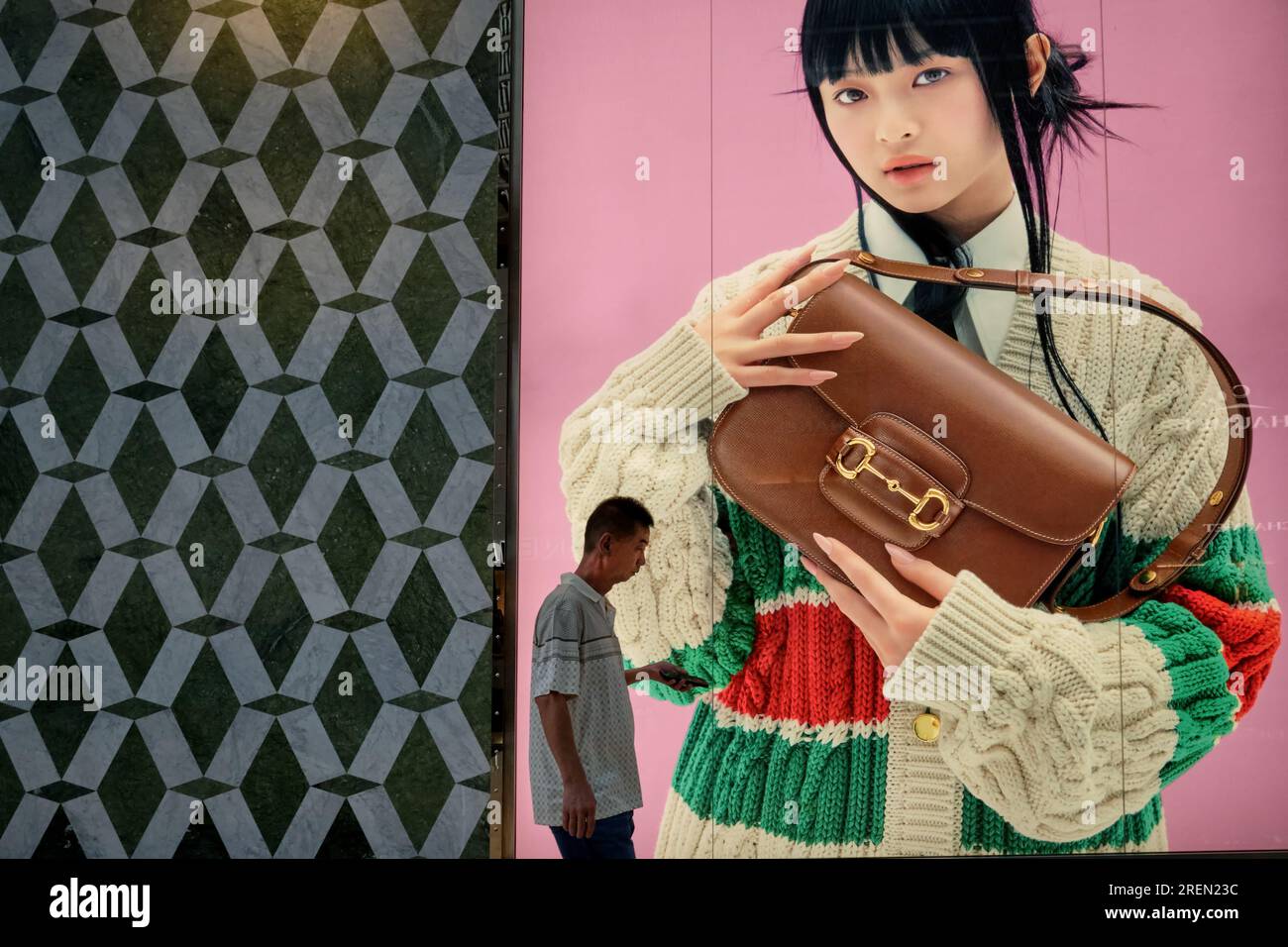 An ethnic Chinese man passes a huge Gucci advertisement at The Shoppes ...