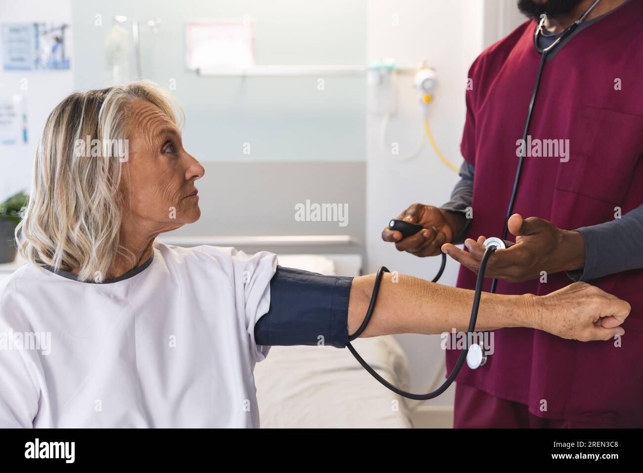 African american male doctor measuring blood pressure of senior female ...