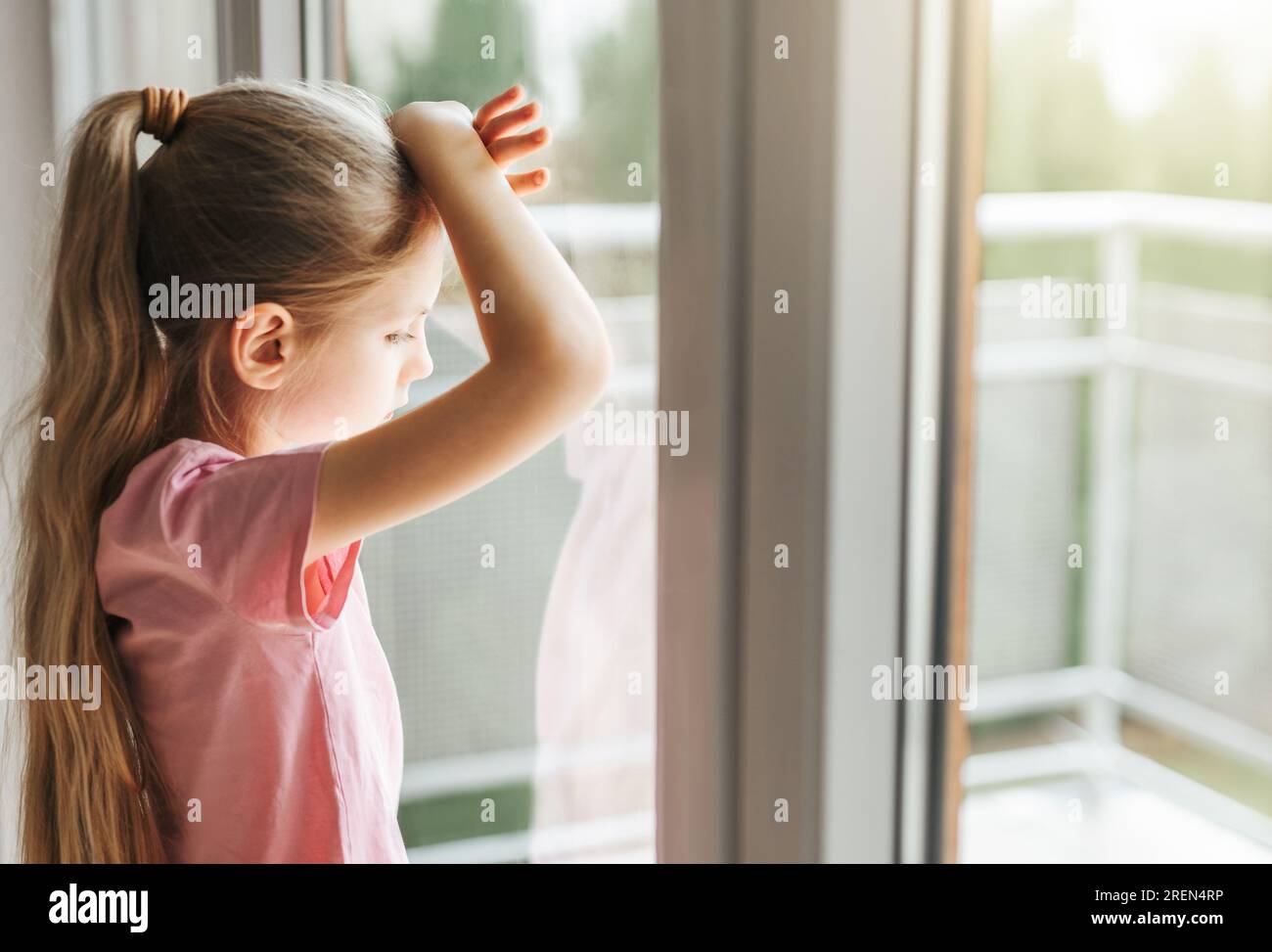 Lonely little girl looking out window, standing at home alone Stock Photo - Alamy