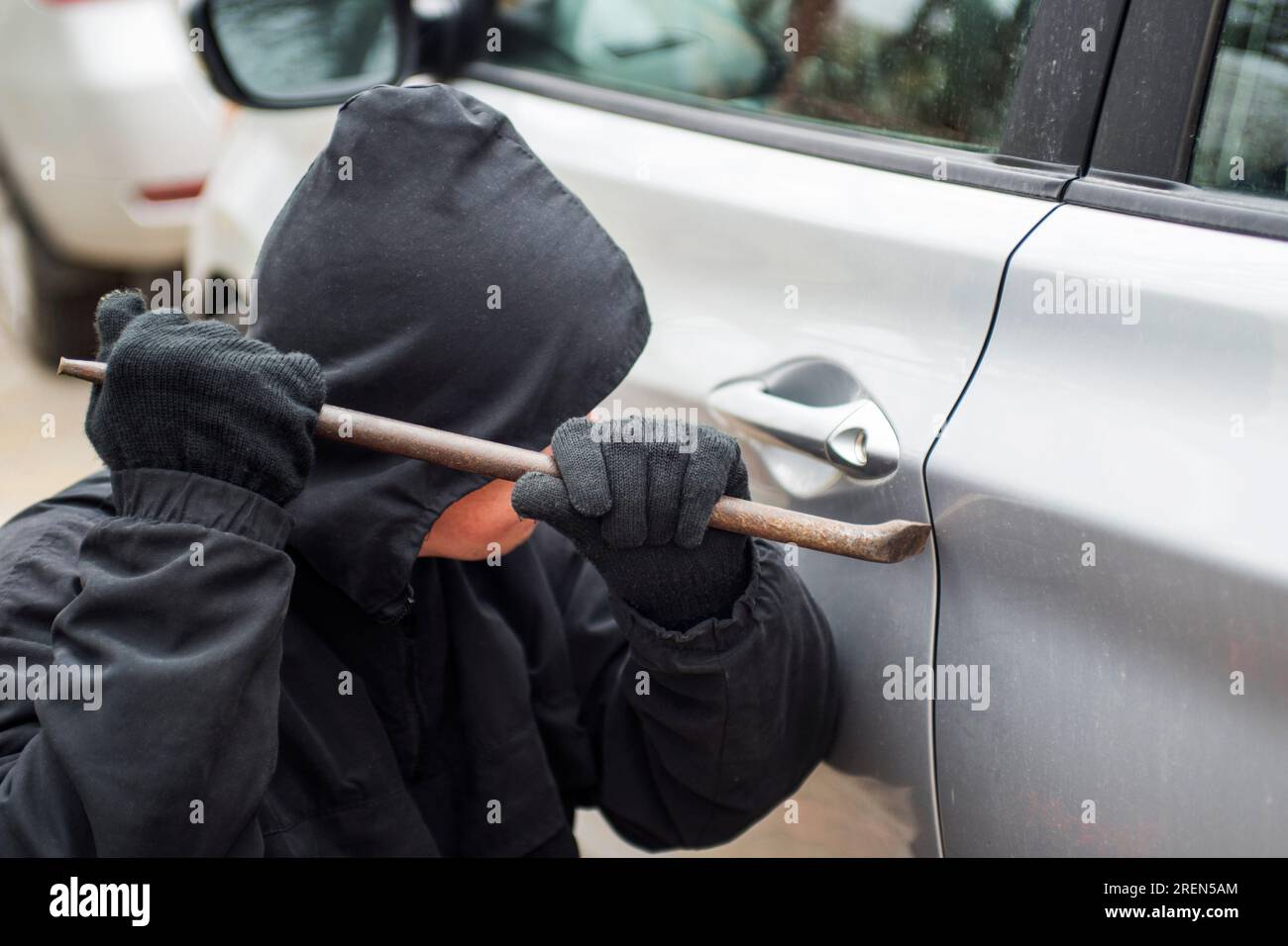 Robber man in black hoodie jacket using crowbar to break lock and steal ...