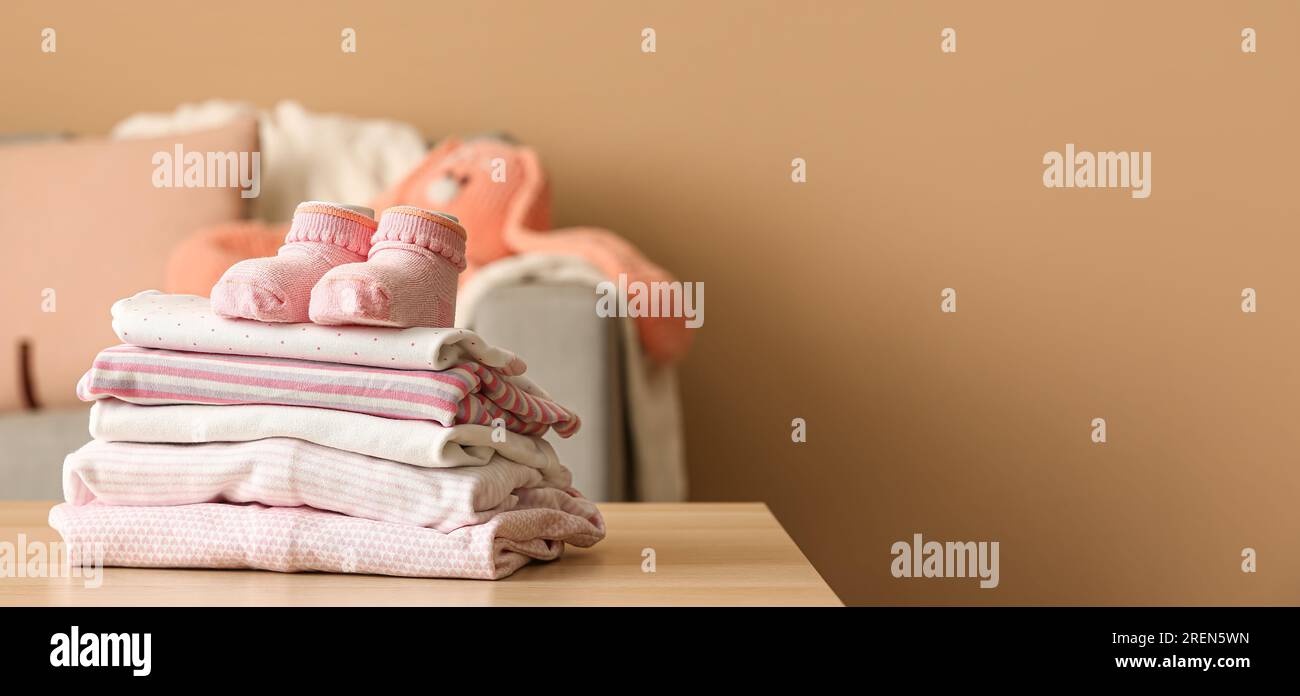 Stack of baby clothes and socks on table in room. Banner for design ...