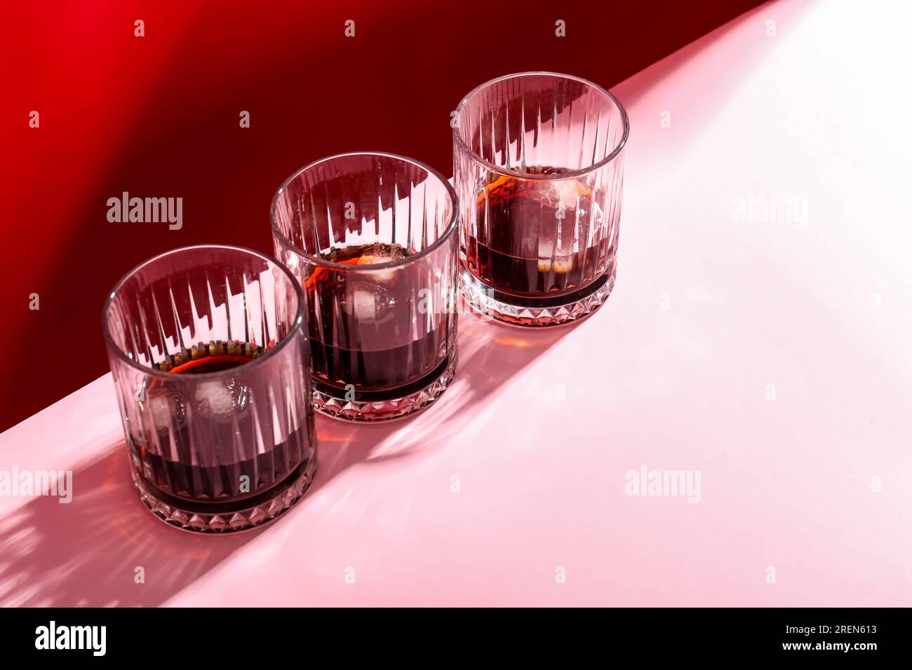 Glasses of rum with ice cubes on pink background Stock Photo - Alamy