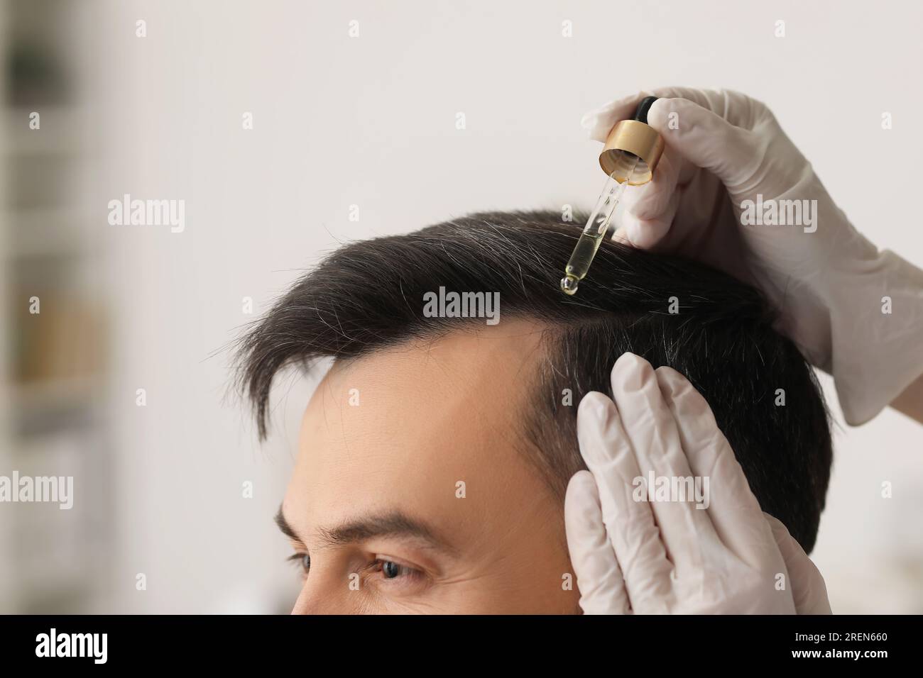 Doctor applying serum on young man's hair in clinic, closeup Stock ...