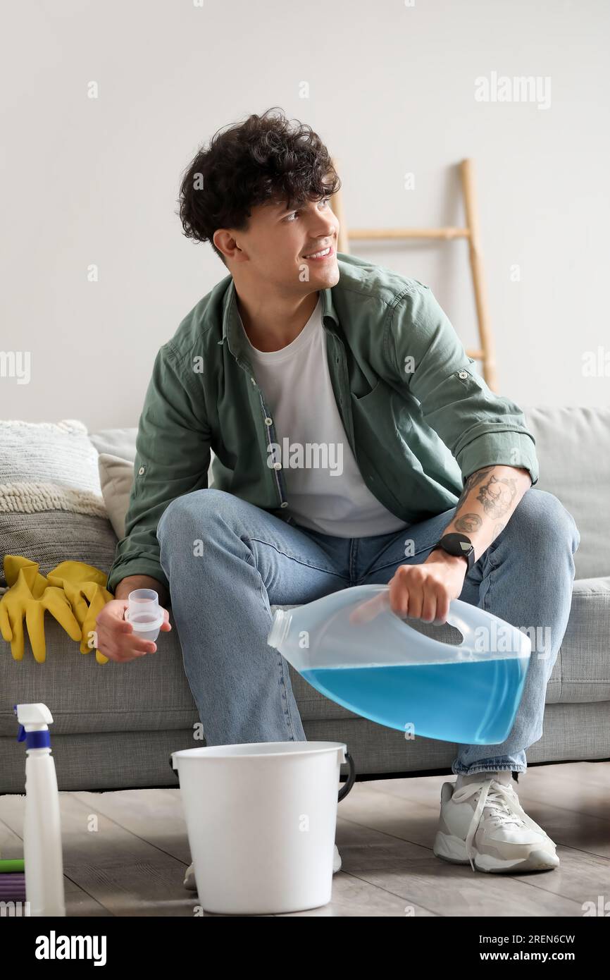 Young man pouring detergent into bucket at home Stock Photo - Alamy
