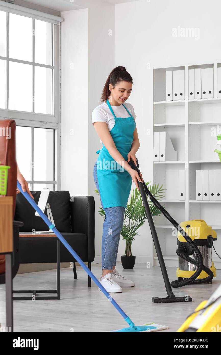Female janitor vacuuming floor in office Stock Photo - Alamy