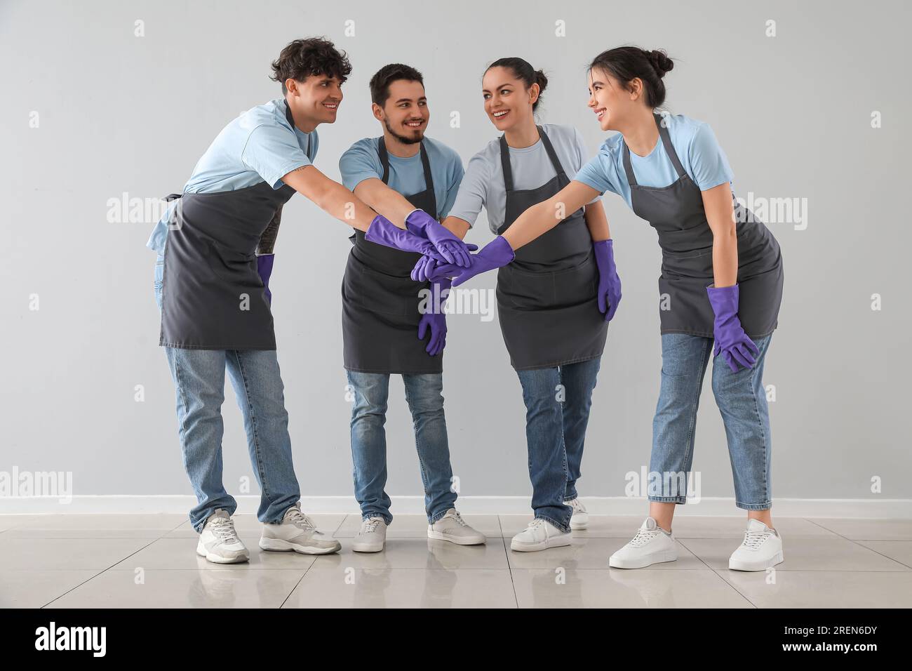 Young janitors putting hands together near grey wall Stock Photo - Alamy