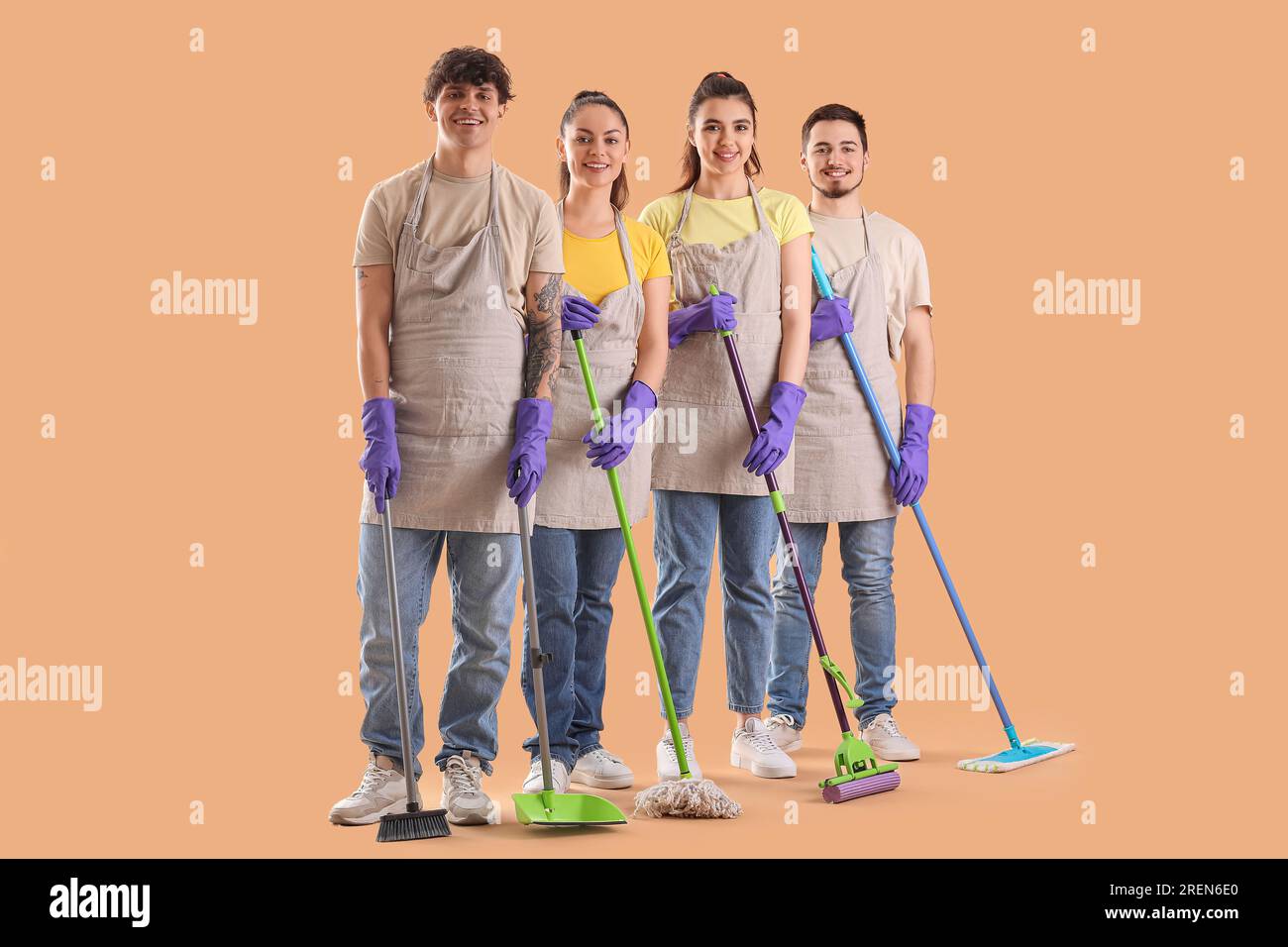 Young janitors with cleaning supplies on beige background Stock Photo ...