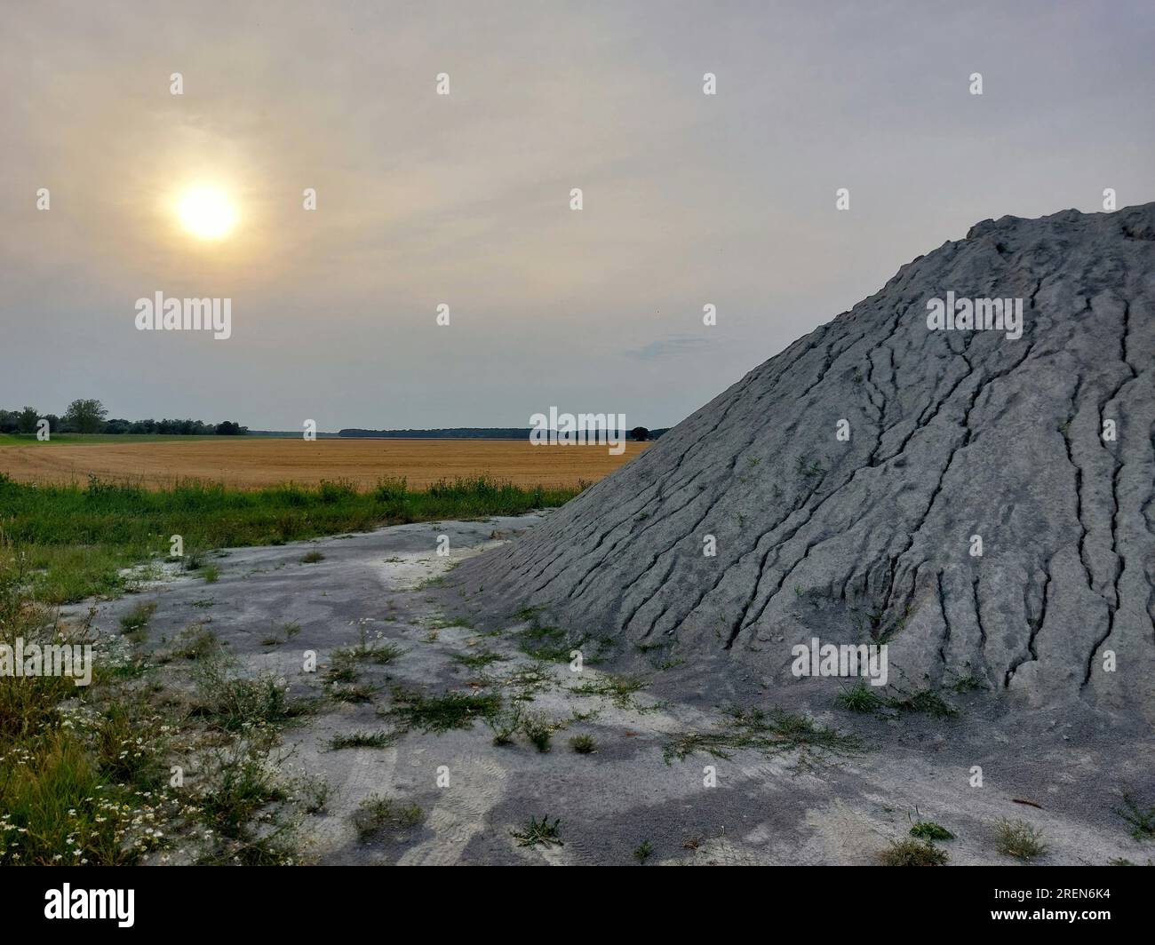 Agricultural landscape with grey heap of cement or gravel, looking like ...