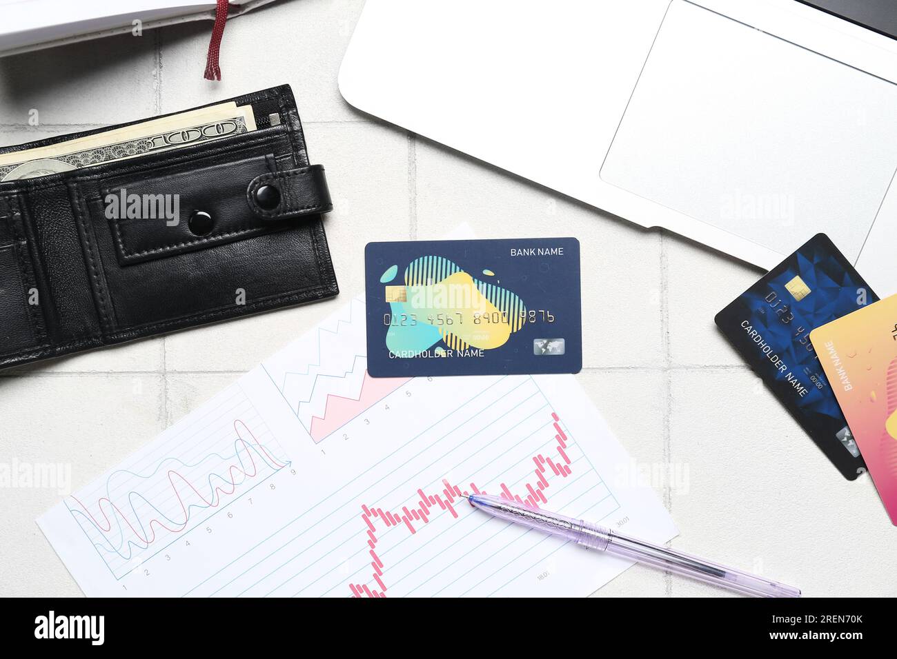 Wallet with money, credit cards and graphics on white tile table Stock ...