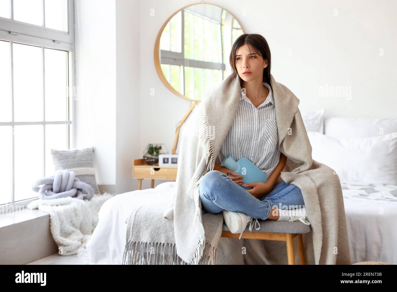 Young woman with hot water bottle suffering from menstrual cramps in ...