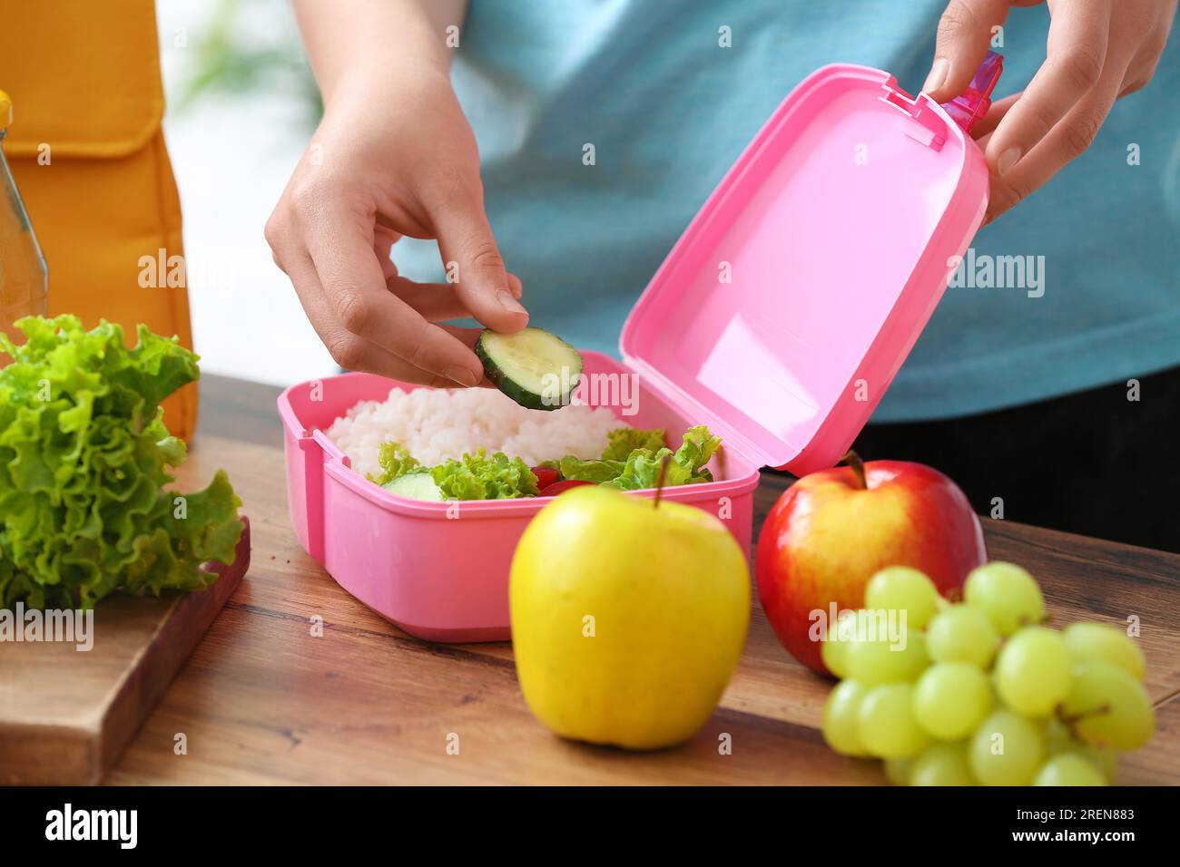 Woman packing fresh meal into lunch box in kitchen Stock Photo - Alamy