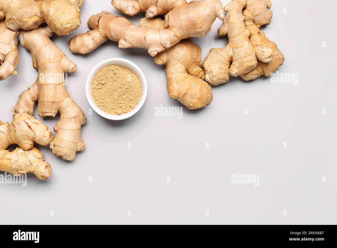 Fresh ginger roots and bowl with dried powder on grey background Stock ...