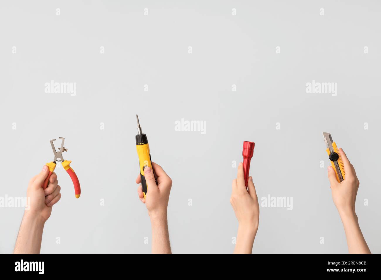 Electrician hands with tools on grey background Stock Photo - Alamy