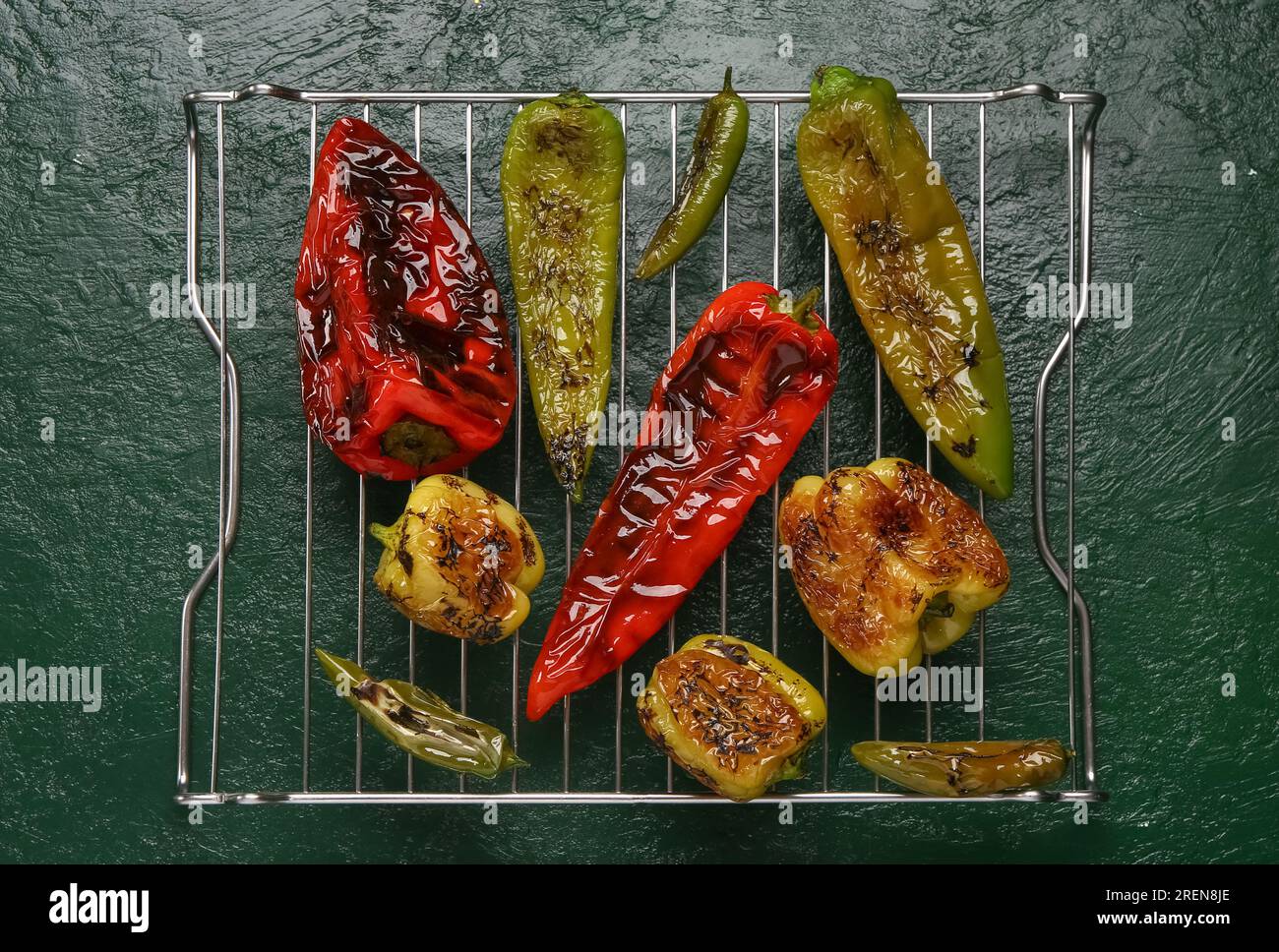Cooling rack with different grilled peppers on green background Stock ...