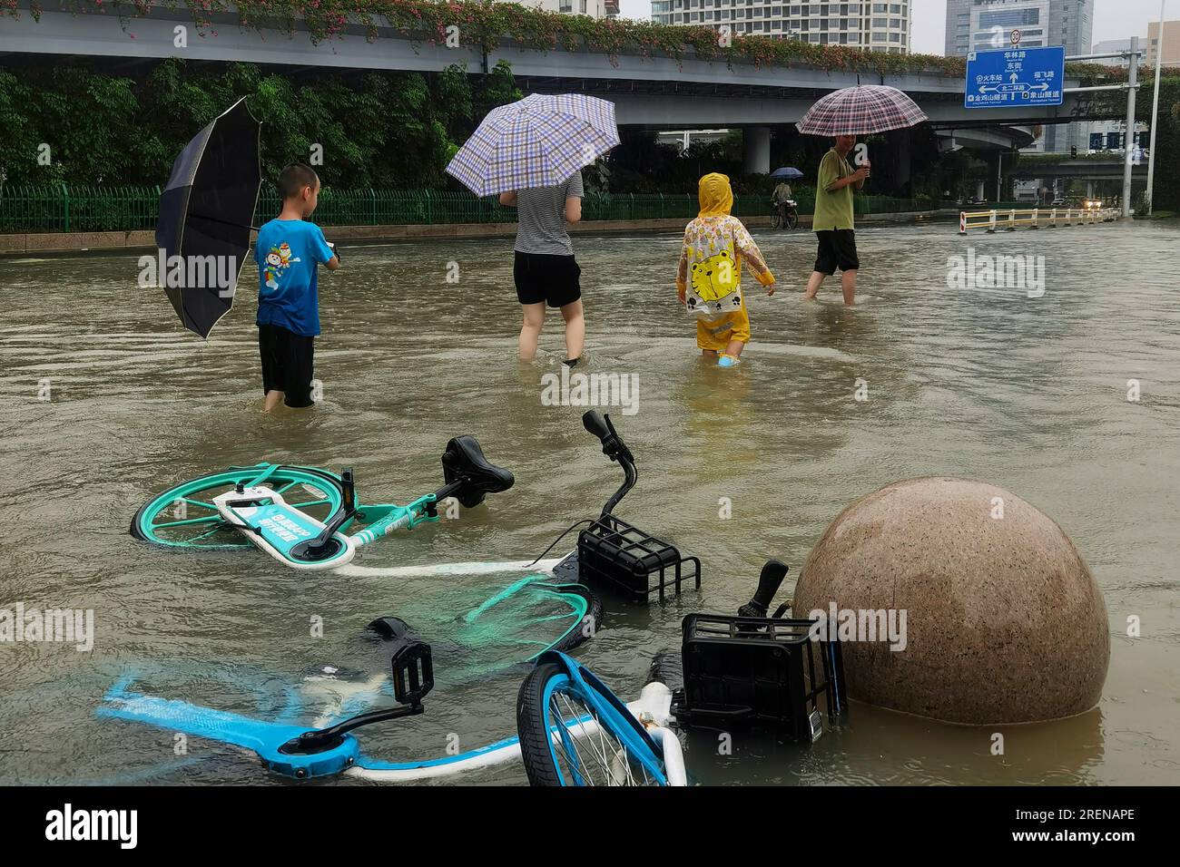 Residents walk through flood waters in the aftermath of Typhoon Doksuri ...