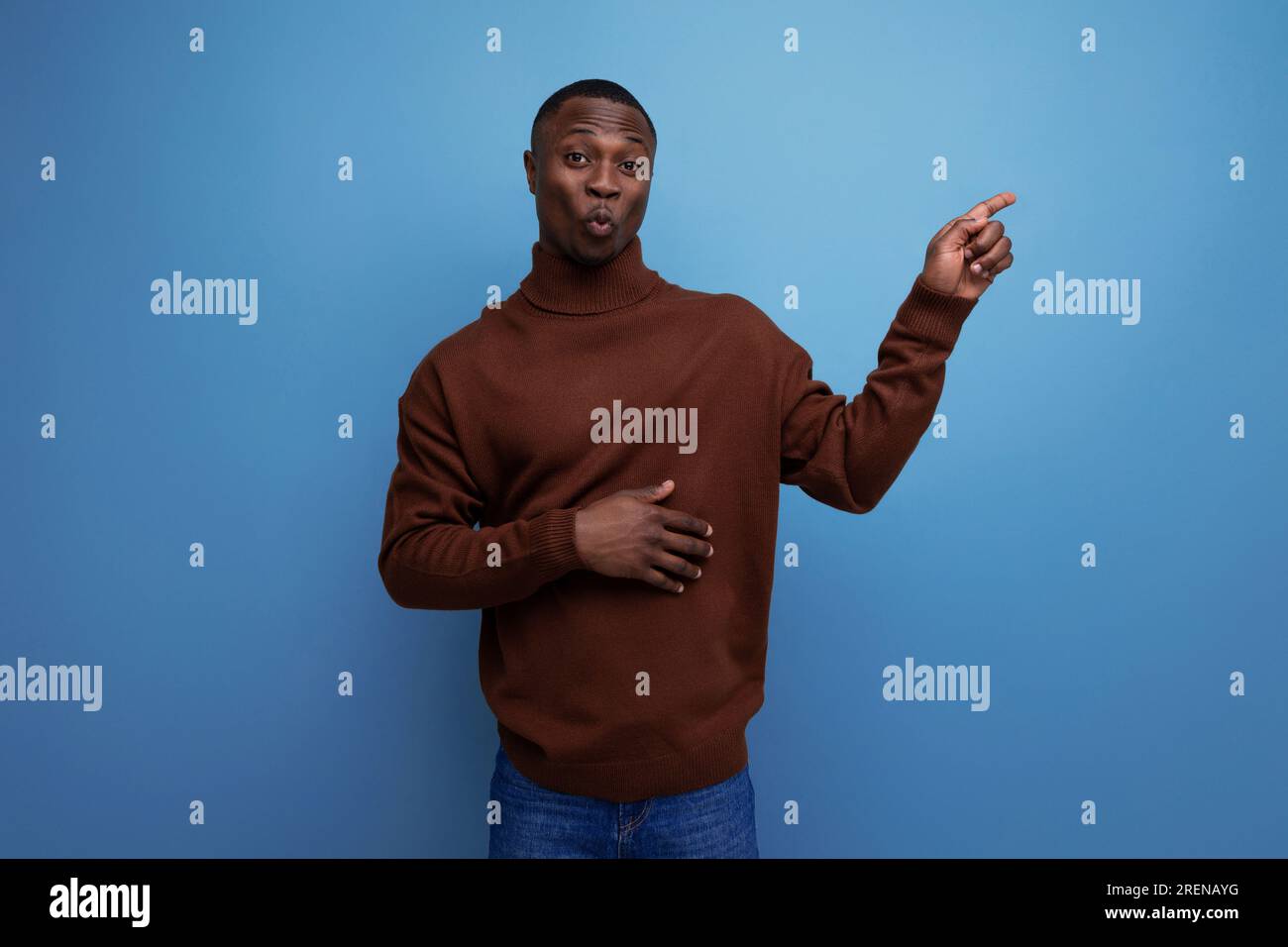 young african man pointing his index finger to the side in studio ...