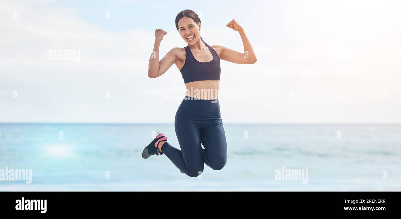 Portrait, freedom and fitness woman jump at the beach with celebration ...