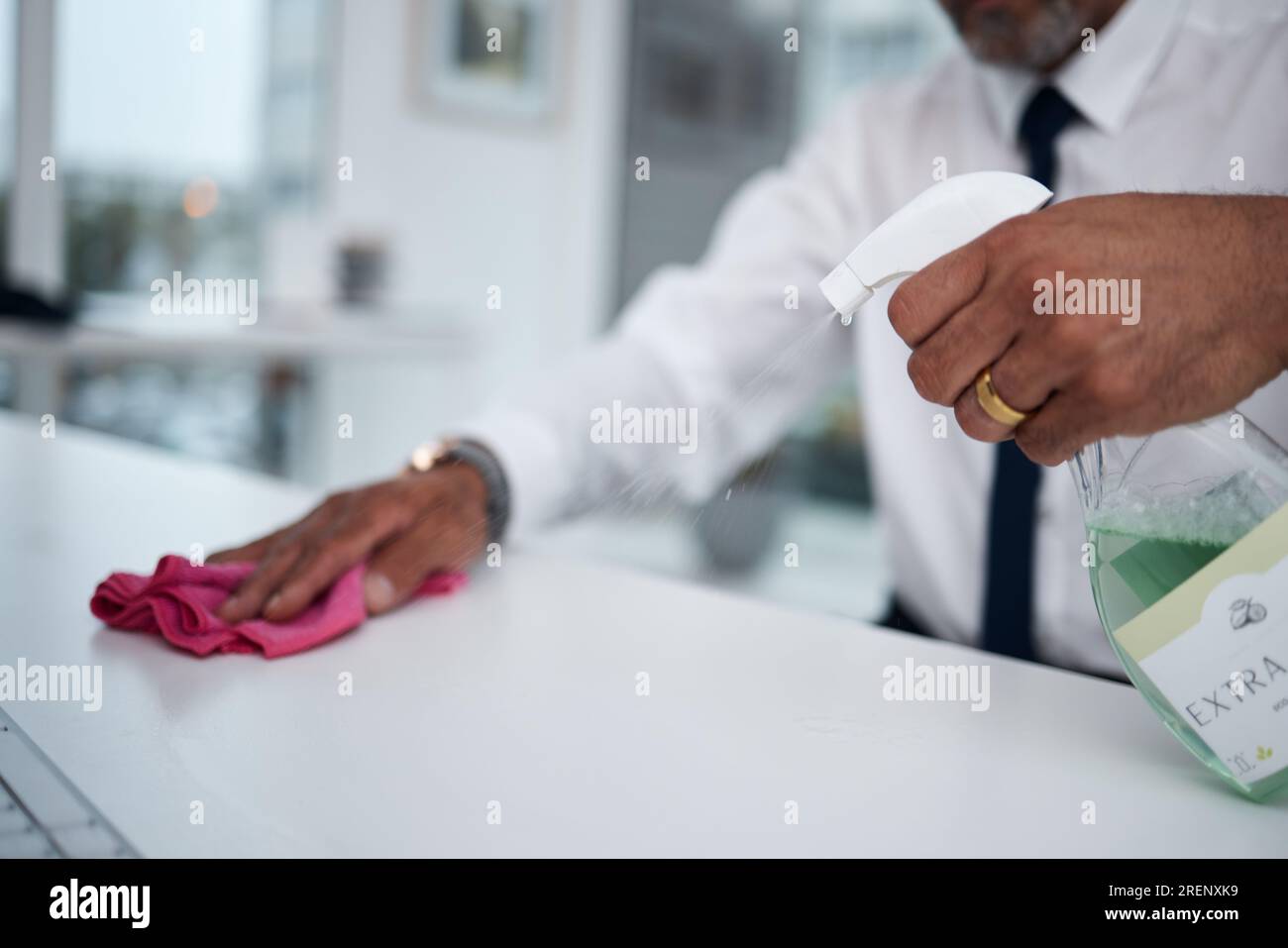Man, hands and cleaning table in office with cloth, spray bottle and ...