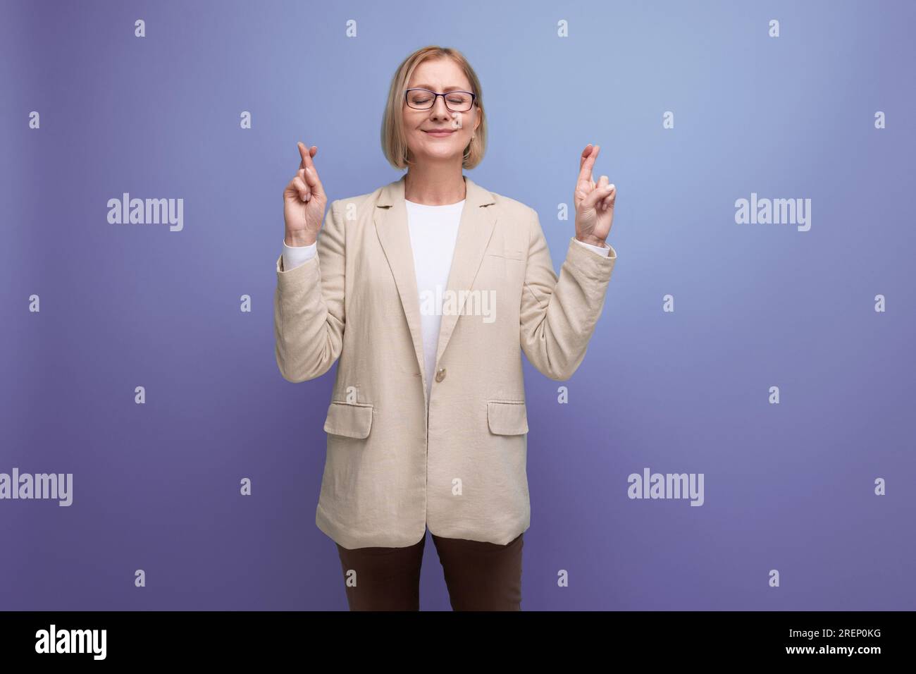 joyful smiling 50s mature woman crossed her fingers with hope on a ...