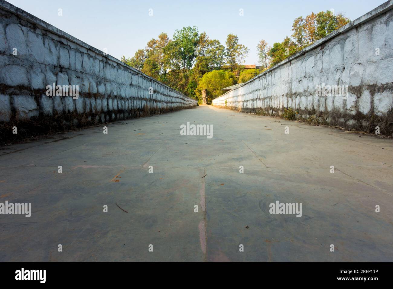 Grounded shot of a narrow sidewalk with stone walls on both sides in an ...