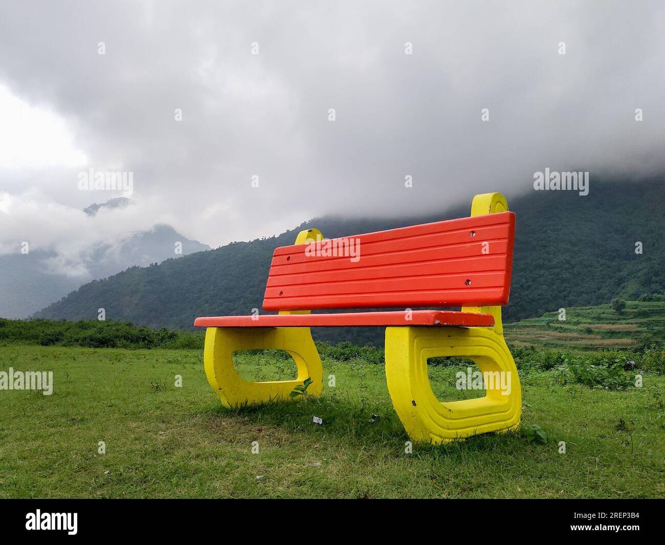Colorful sitting bench on a serene hilltop meadow with mountains and a ...