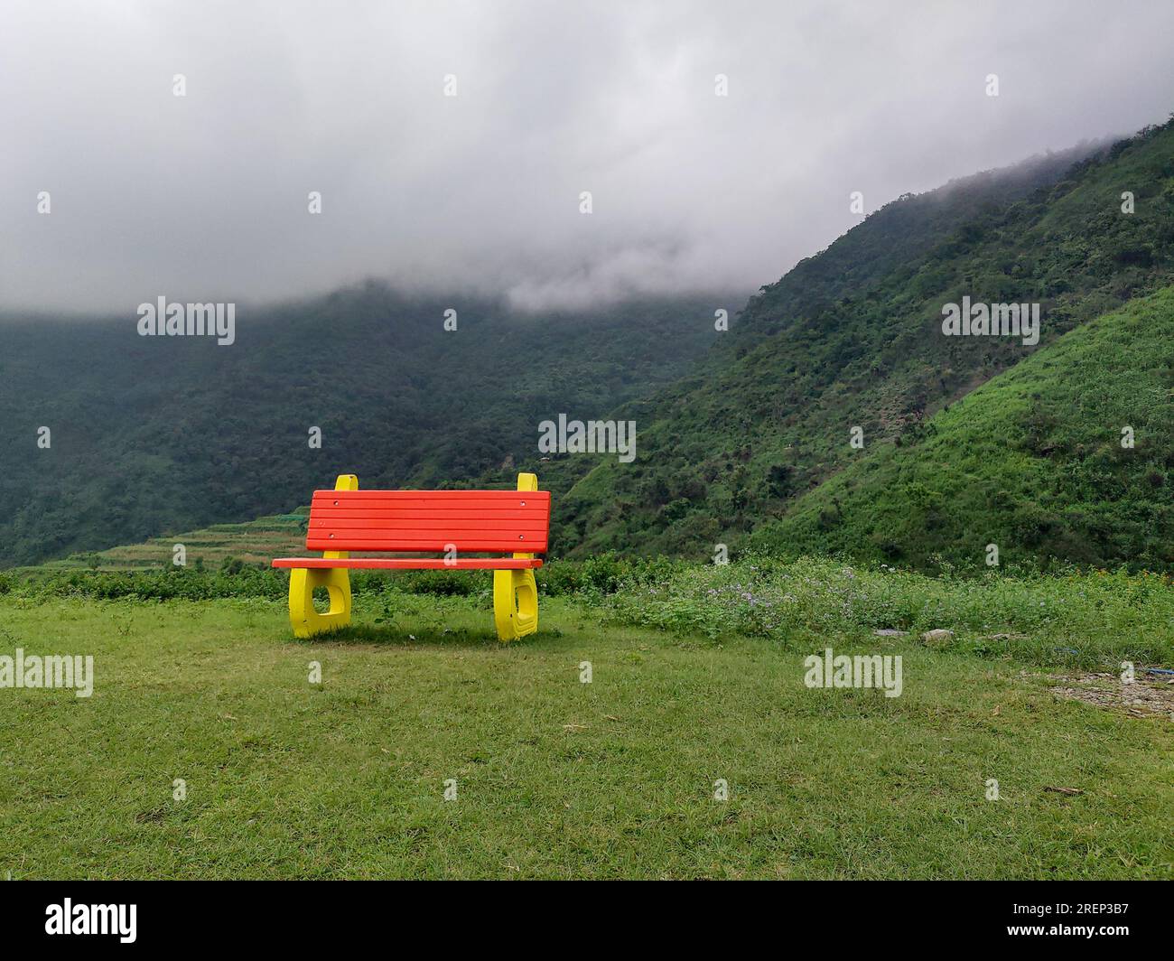 Colorful sitting bench on a serene hilltop meadow with mountains and a ...