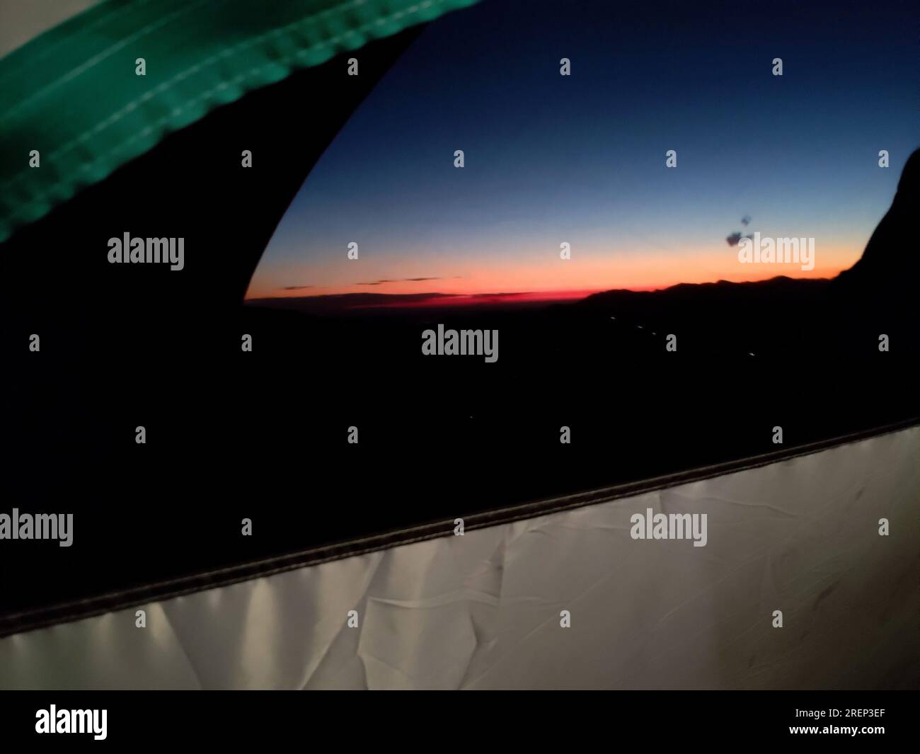 Mesmerizing orange horizon over mountain peaks, seen from inside a tent ...