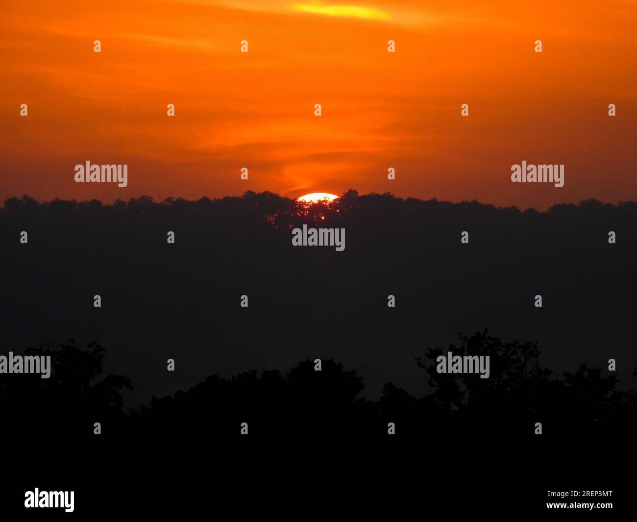 Spectacular sunset casting mountain and forest silhouettes at dusk in ...