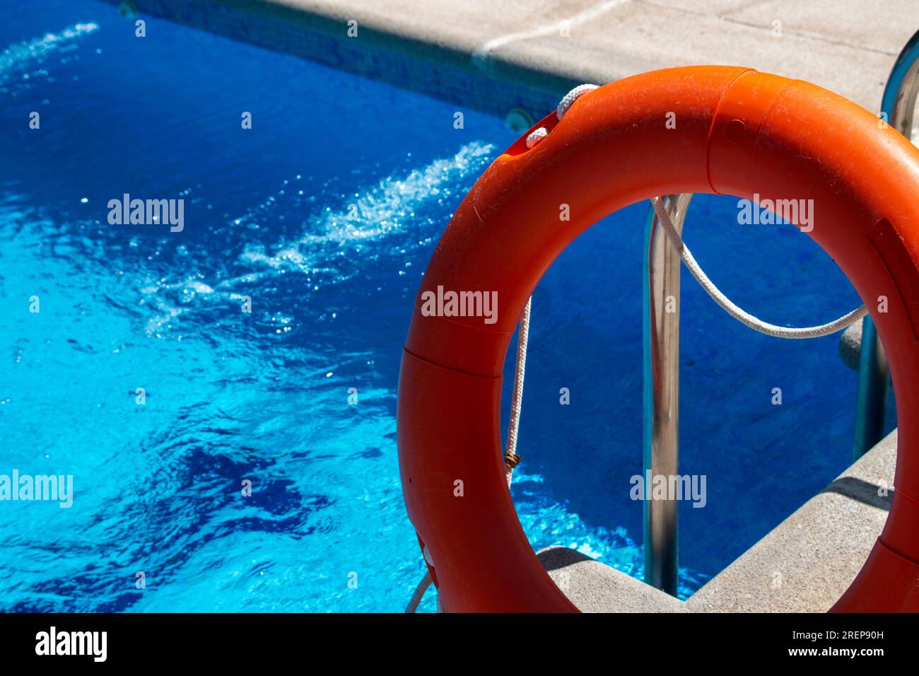 Orange rescue float resting on the steel ladder of a swimming pool ...