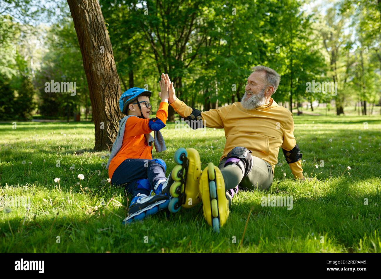 Happy father and son giving high five each other while rest on meadow ...