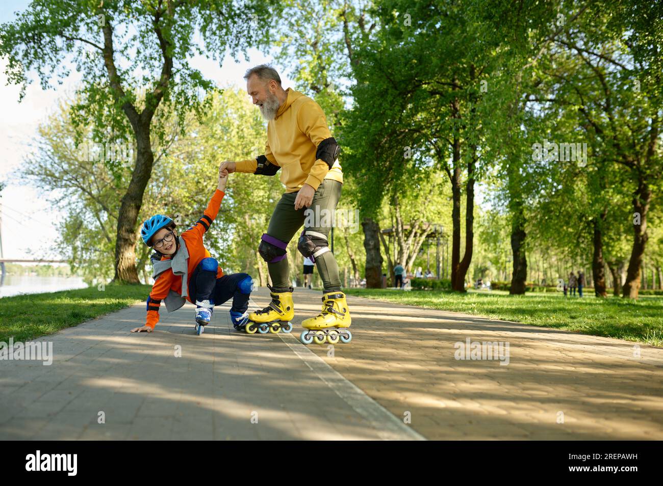 Senior man roller skating with little boy in urban park Stock Photo - Alamy