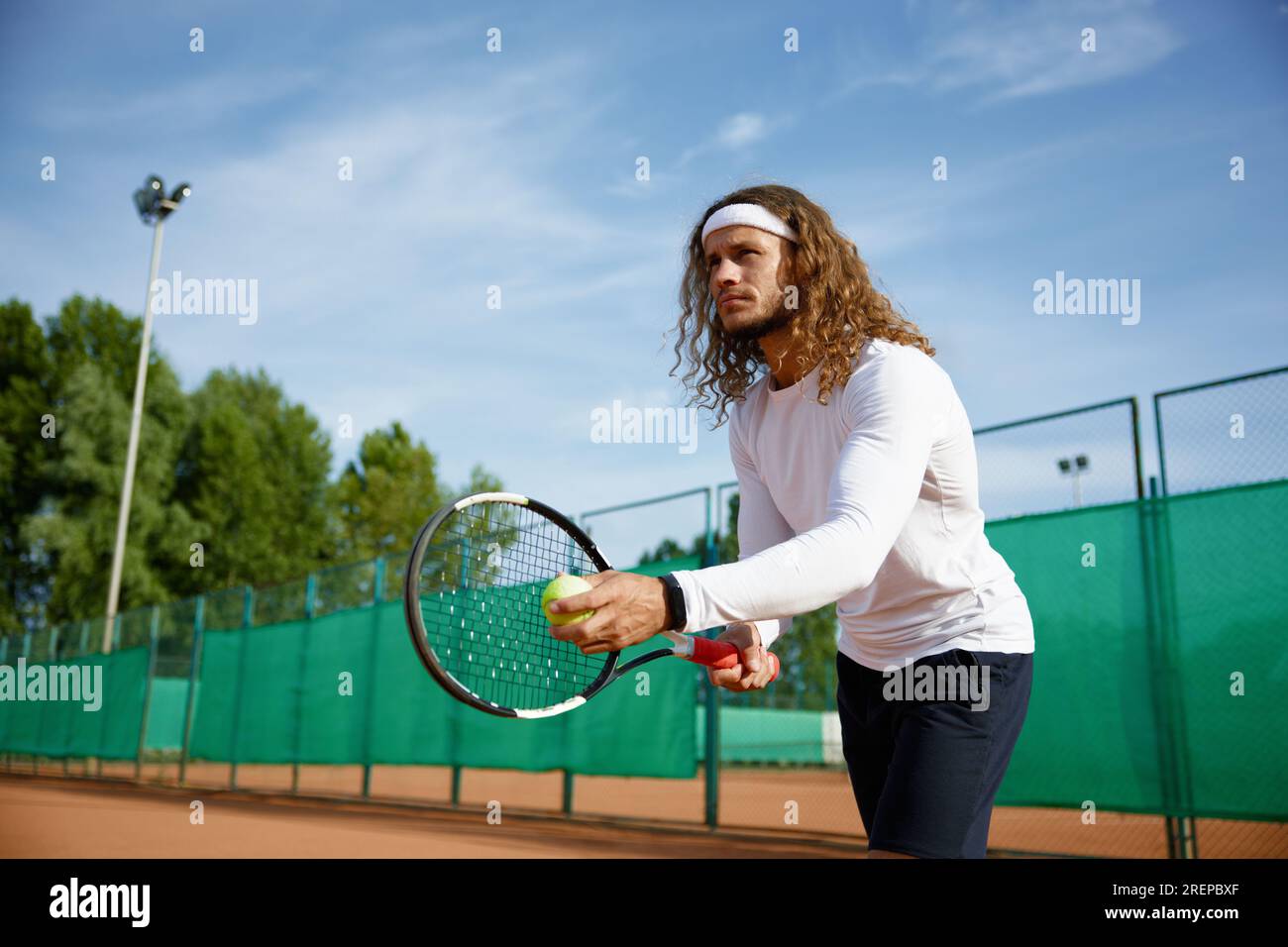 Concentrated male tennis player with racket and ball training on ...
