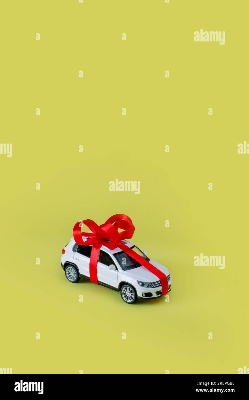 White model car with bow on a yellow background. Car as gift, surprise ...
