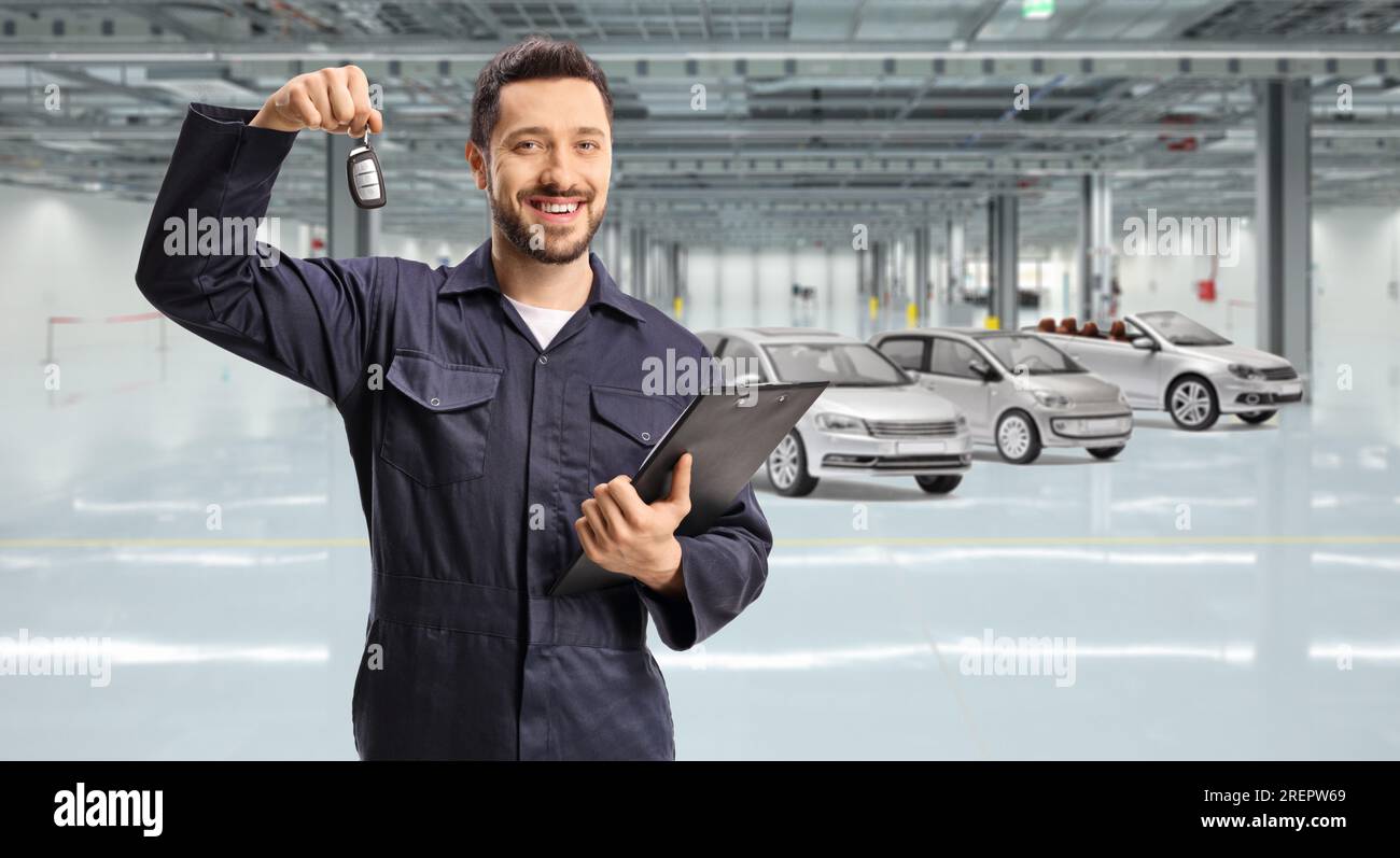 Auto mechanic holding key in a car garage Stock Photo - Alamy