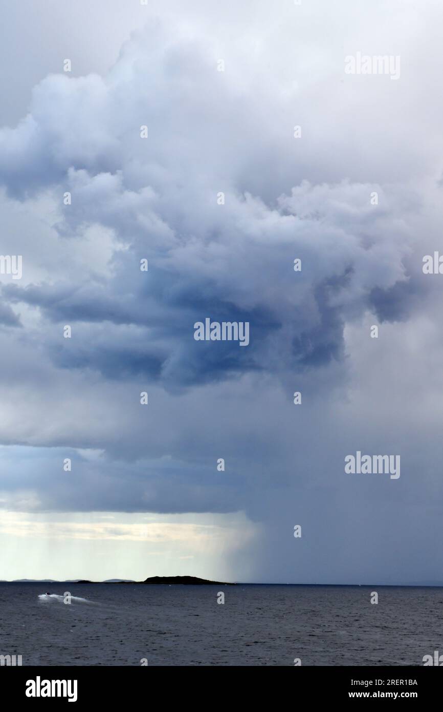Vertical photo of dark clouds and rain above the horizon at sea Stock ...
