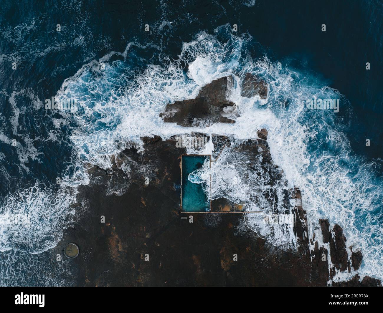 Aerial view early morning light with ocean waves flowing over rock pool ...