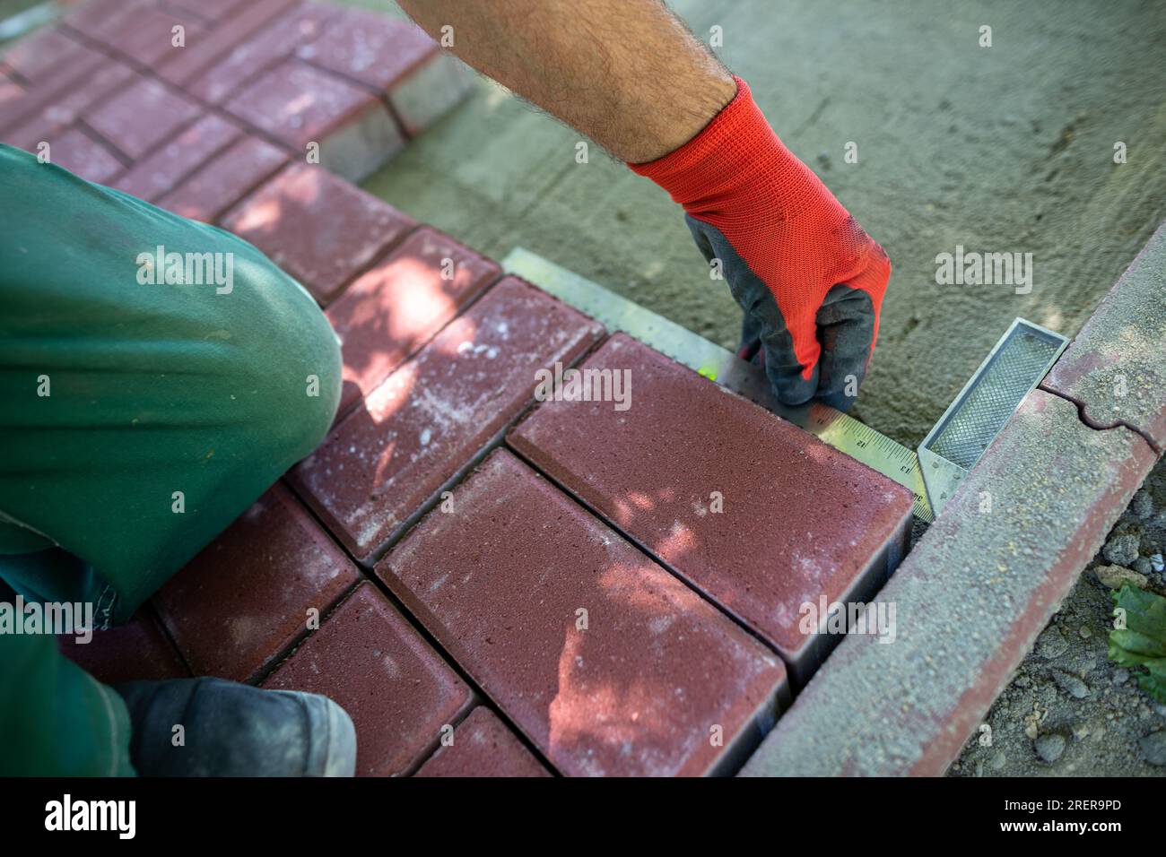 During the laying of paving blocks, the worker checks with a protractor ...