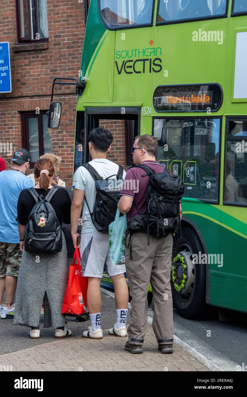 people queueing for a bus on the isle of wight. waiting to board a ...