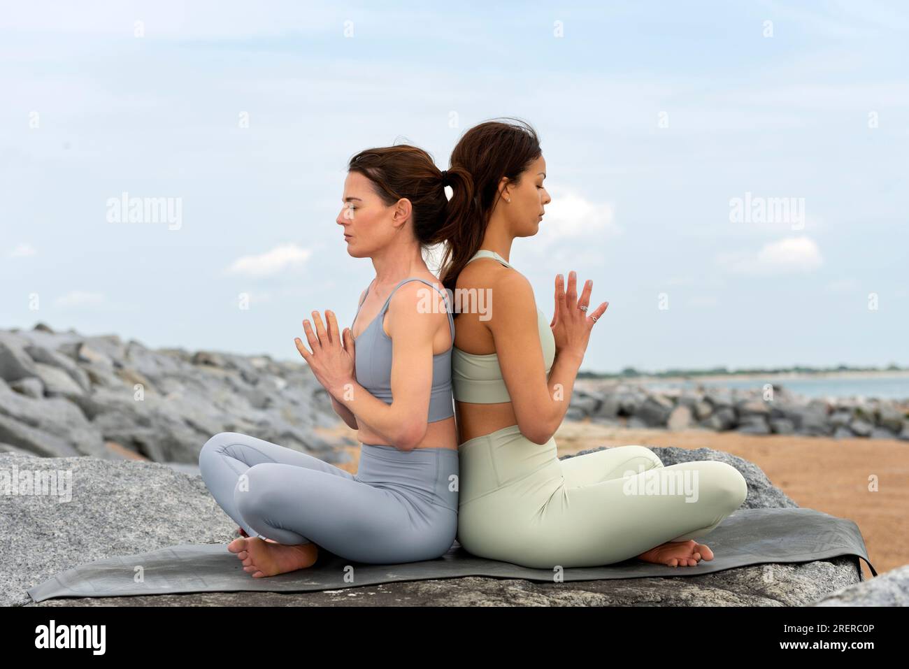 Two women sitting back to back practicing yoga and meditating Stock ...