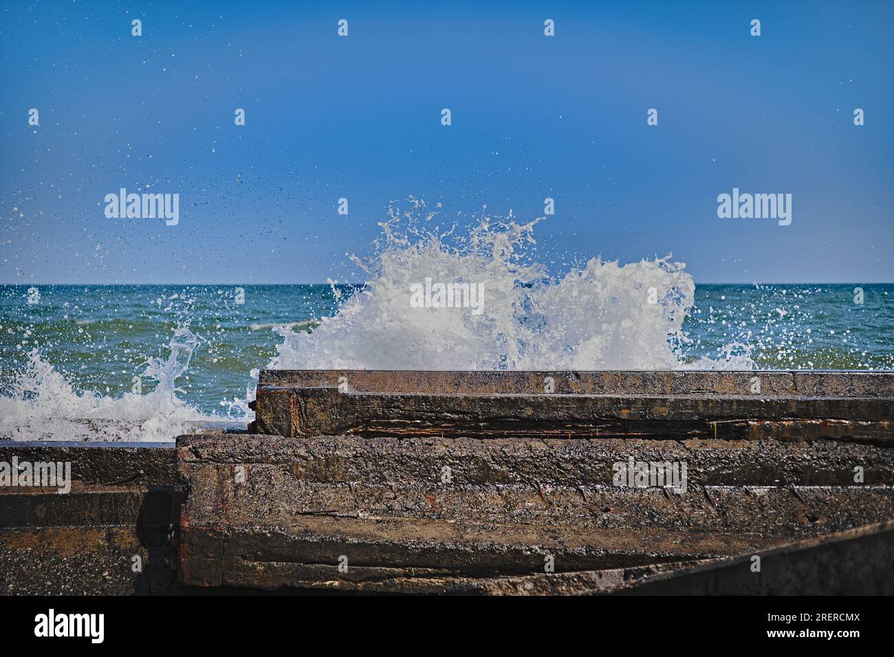 Splash from the waves breaking on the granite embankment with blue ...