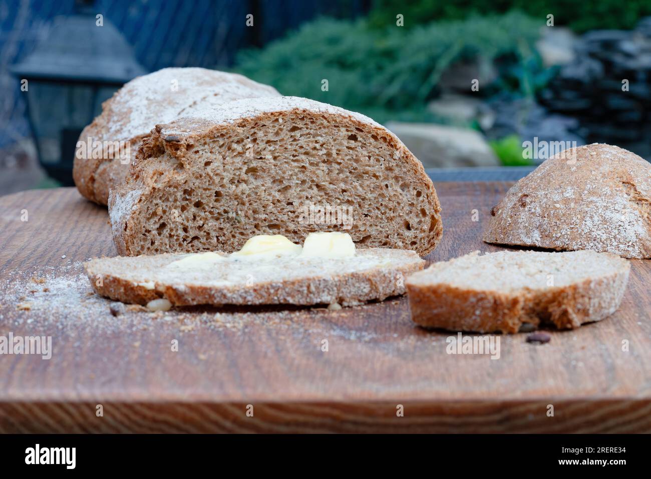 Sliced wholemeal bread is displayed on a wooden board that has a ...