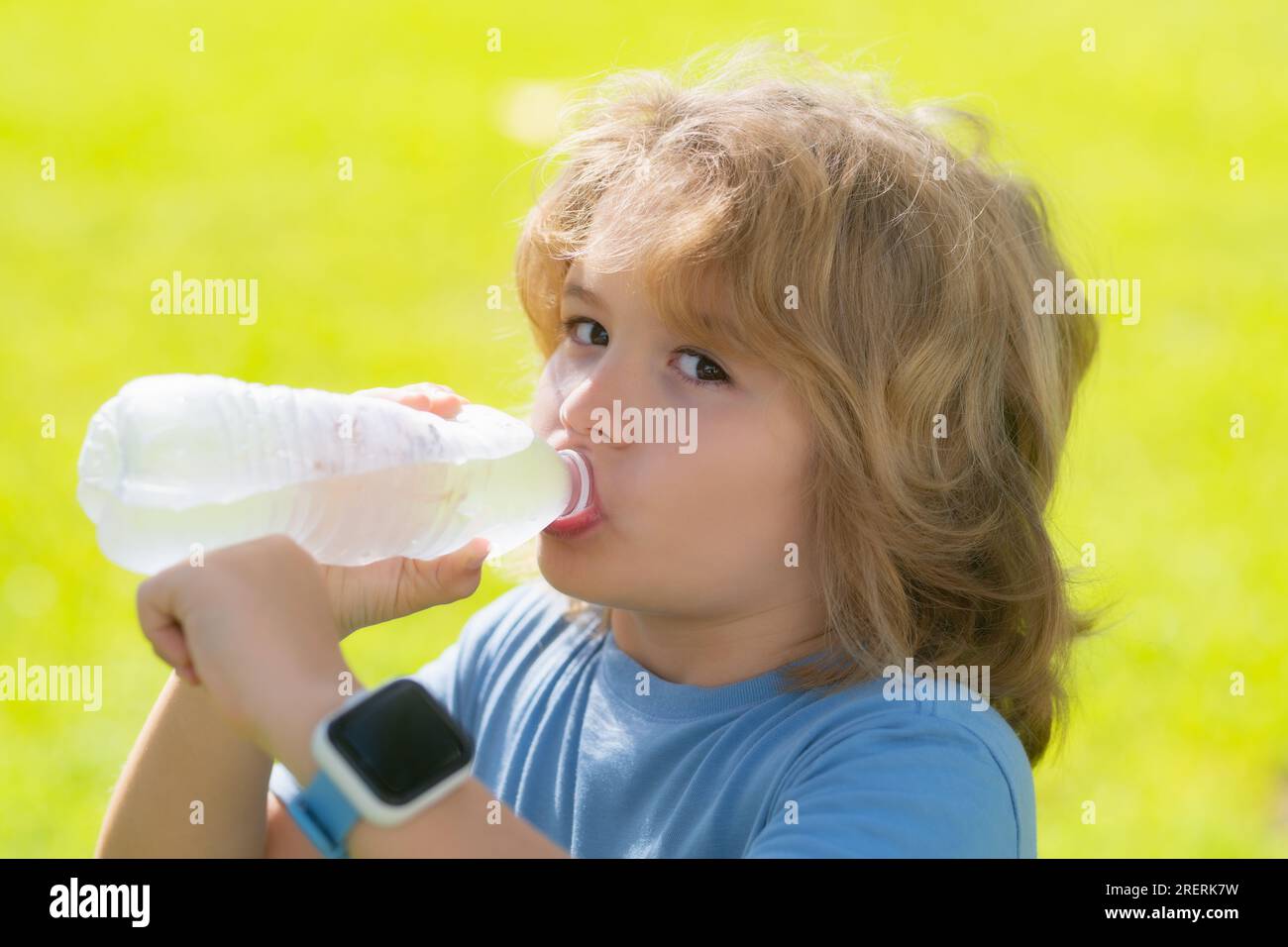 Little kid drinking a fresh bottle of water. Thirsty child holding ...