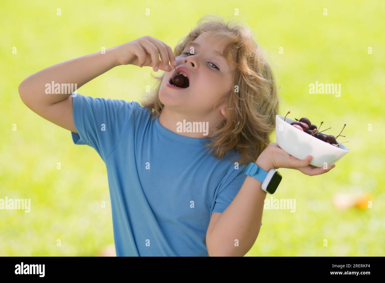Cherry in kids mouth. Cute little boy eating cherries, making funny ...