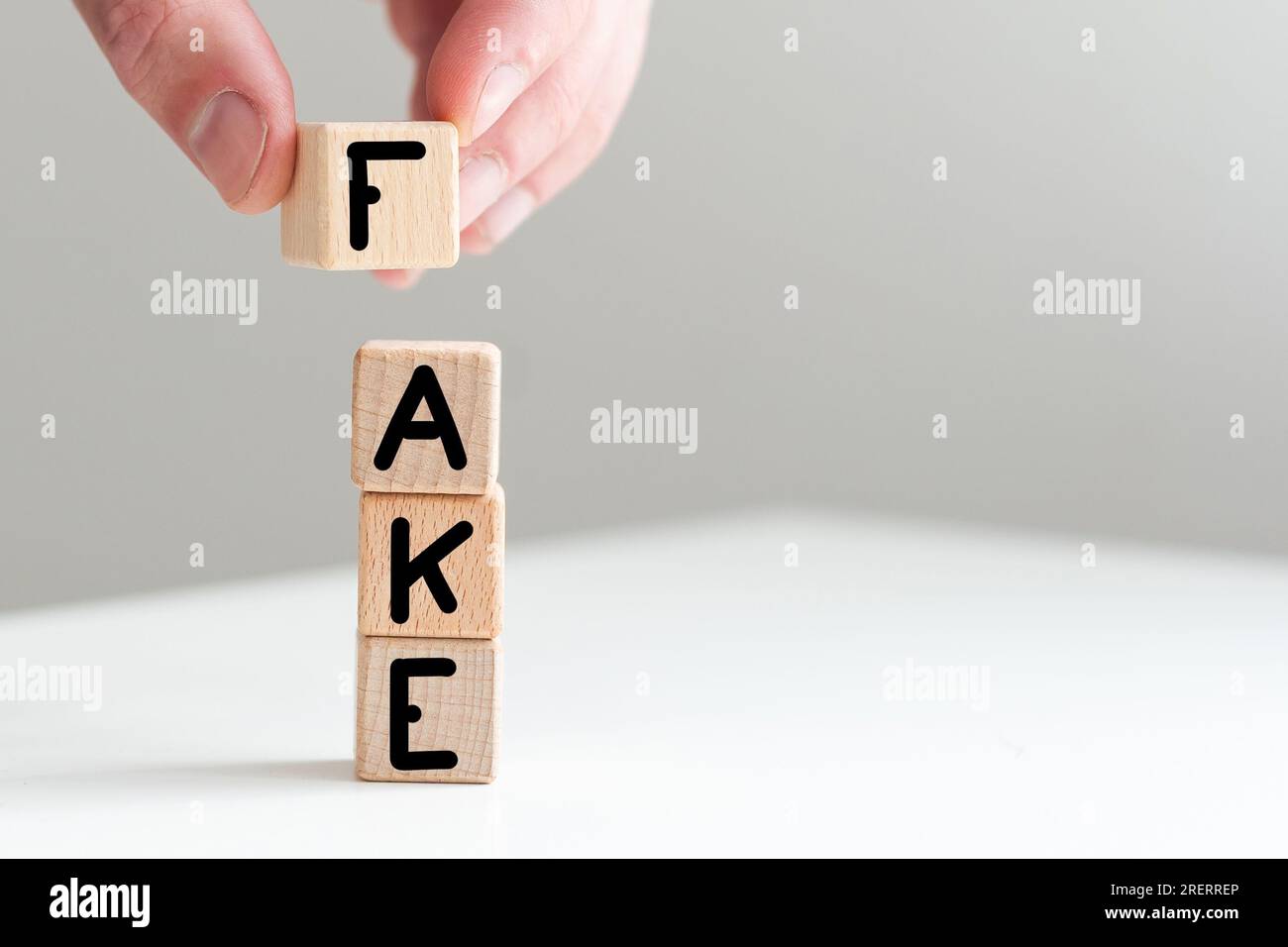 The word 'fake' written on wooden blocks, a man sitting in front of his ...