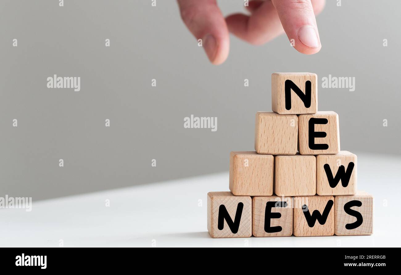 A man in a blue shirt composes the word NEWS from wooden cubes ...