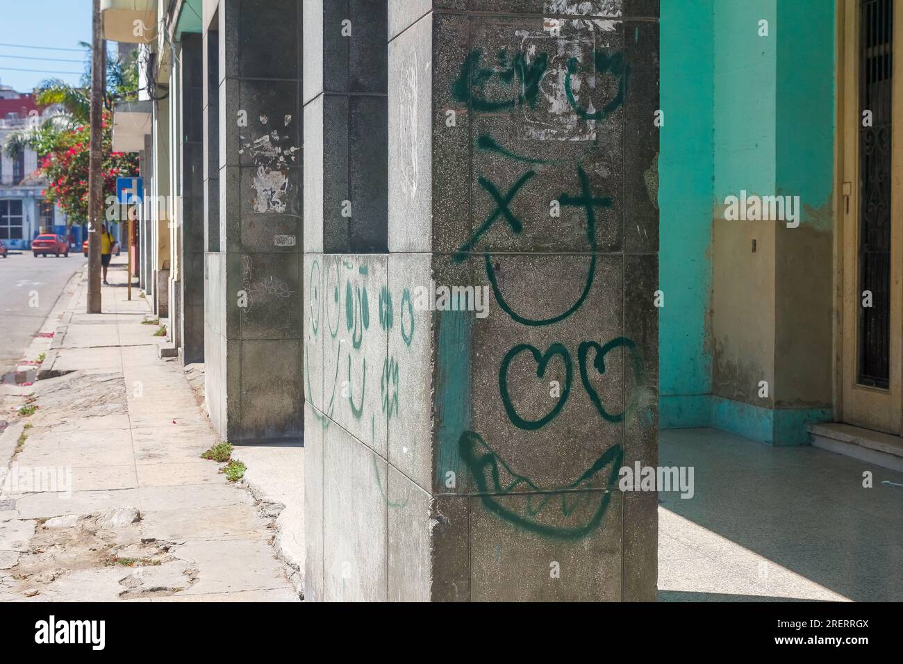Havana, Cuba, Graffiti in a porch columns. A broken sidewalk by an ...