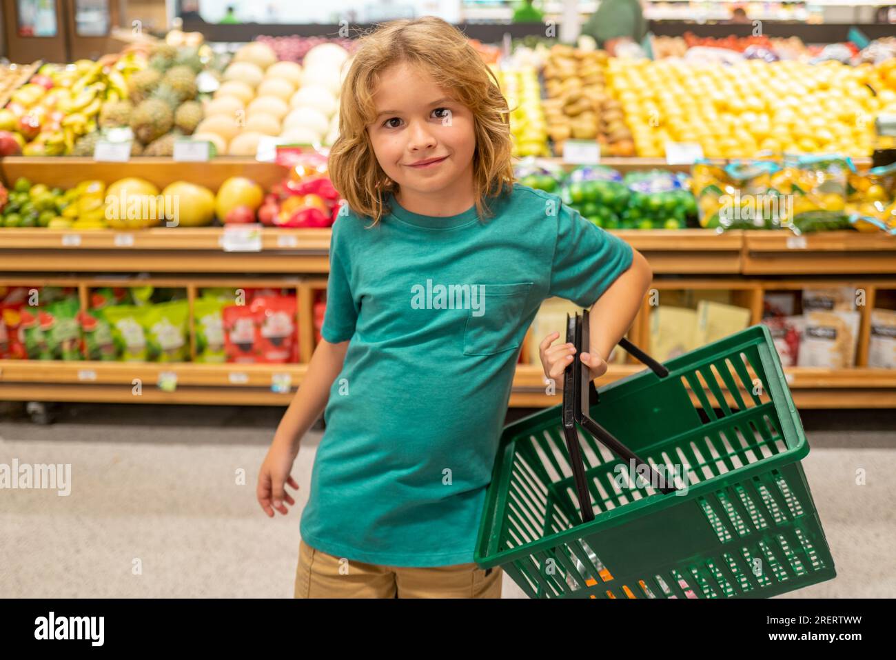 Kids with shopping basket. Kid is choosing fresh vegetables and fruits ...