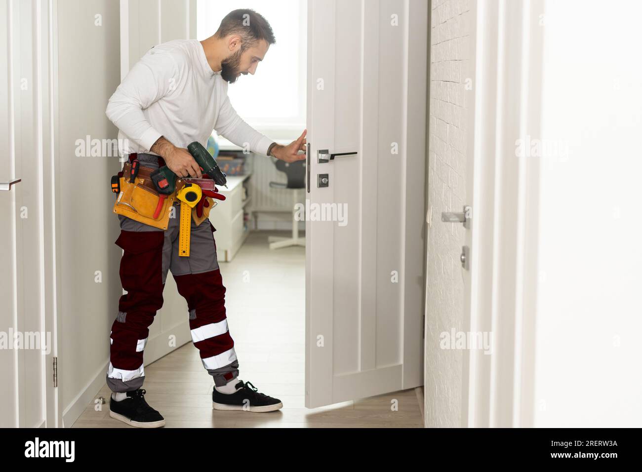 good looking man working as handyman and fixing a door lock in a house ...
