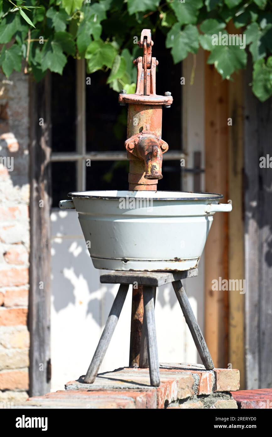 Old vintage water pump with white metal basin in rustic countryside ...